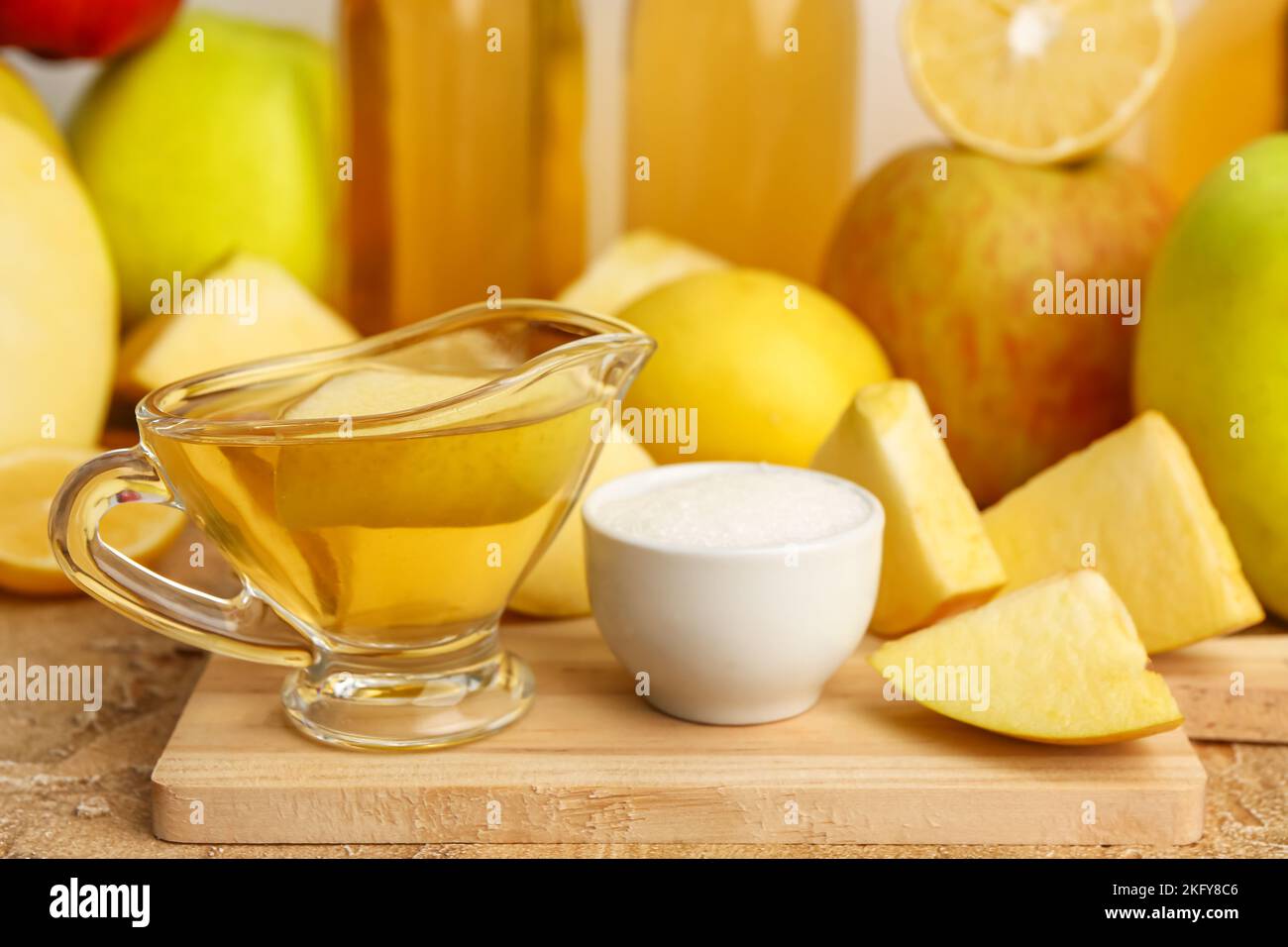 Wooden board with gravy boat of apple cider vinegar, sugar and fruits ...