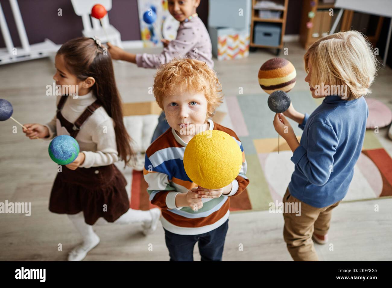 Selective focus on cute little boy holding model of sun while playing ...
