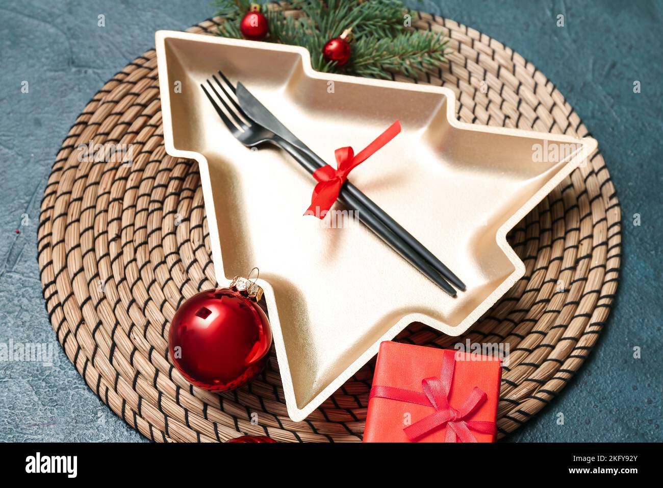 Plate in shape of Christmas tree with cutlery, gift and decor on dark ...