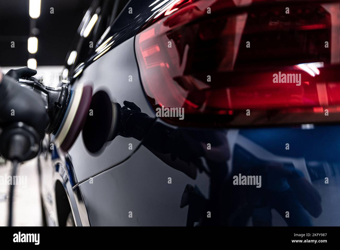 Employee of a car detailing studio polishes the paint of a car Stock ...