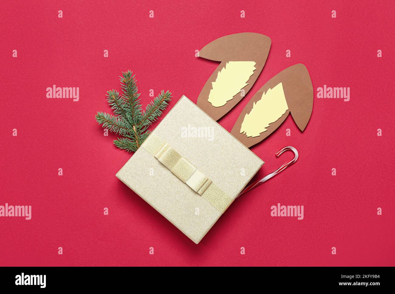 Paper bunny ears with Christmas branches, gift and candy cane on red ...