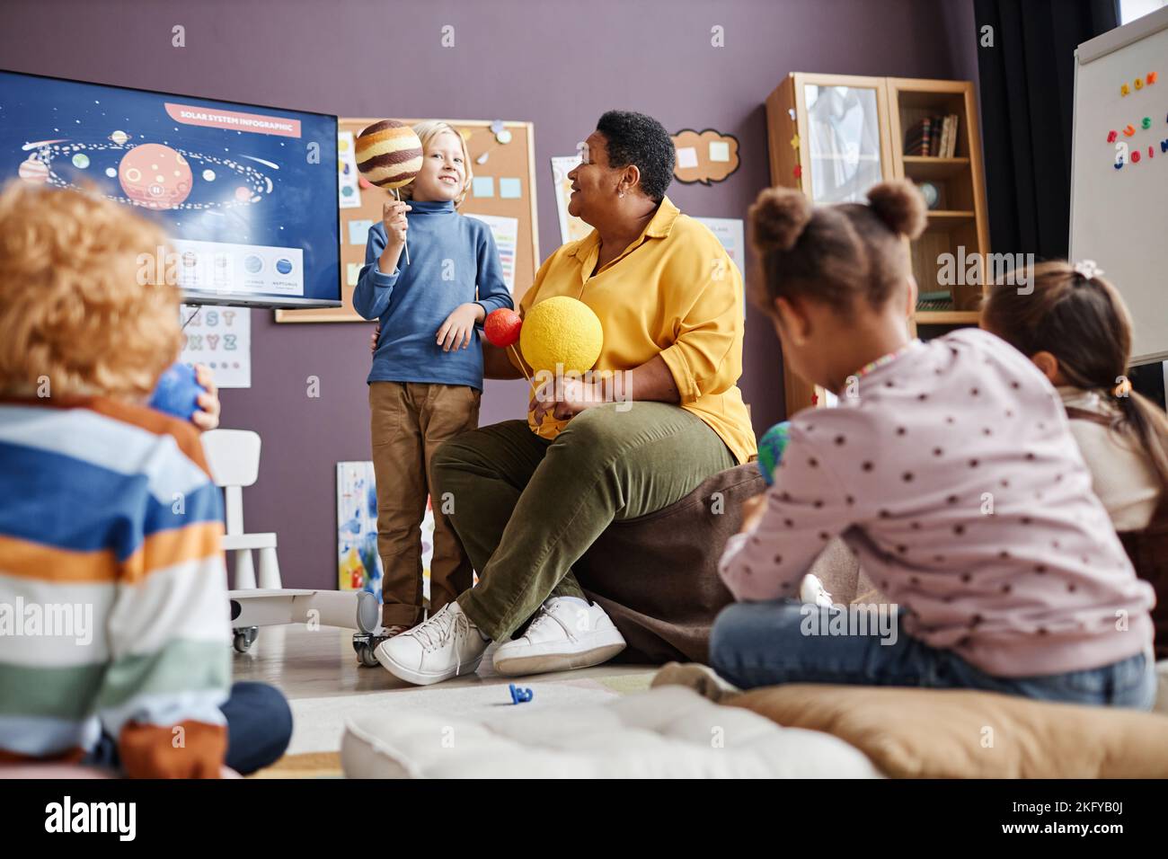 Cute little boy with Jupiter model standing by teacher at lesson of ...