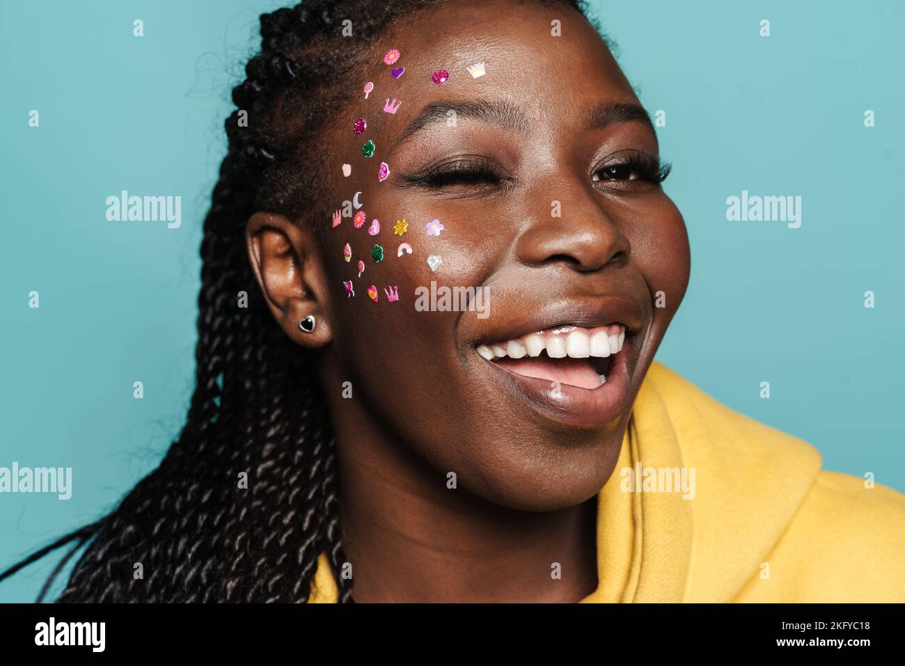 Young black woman with stickers on her face winking at camera isolated ...