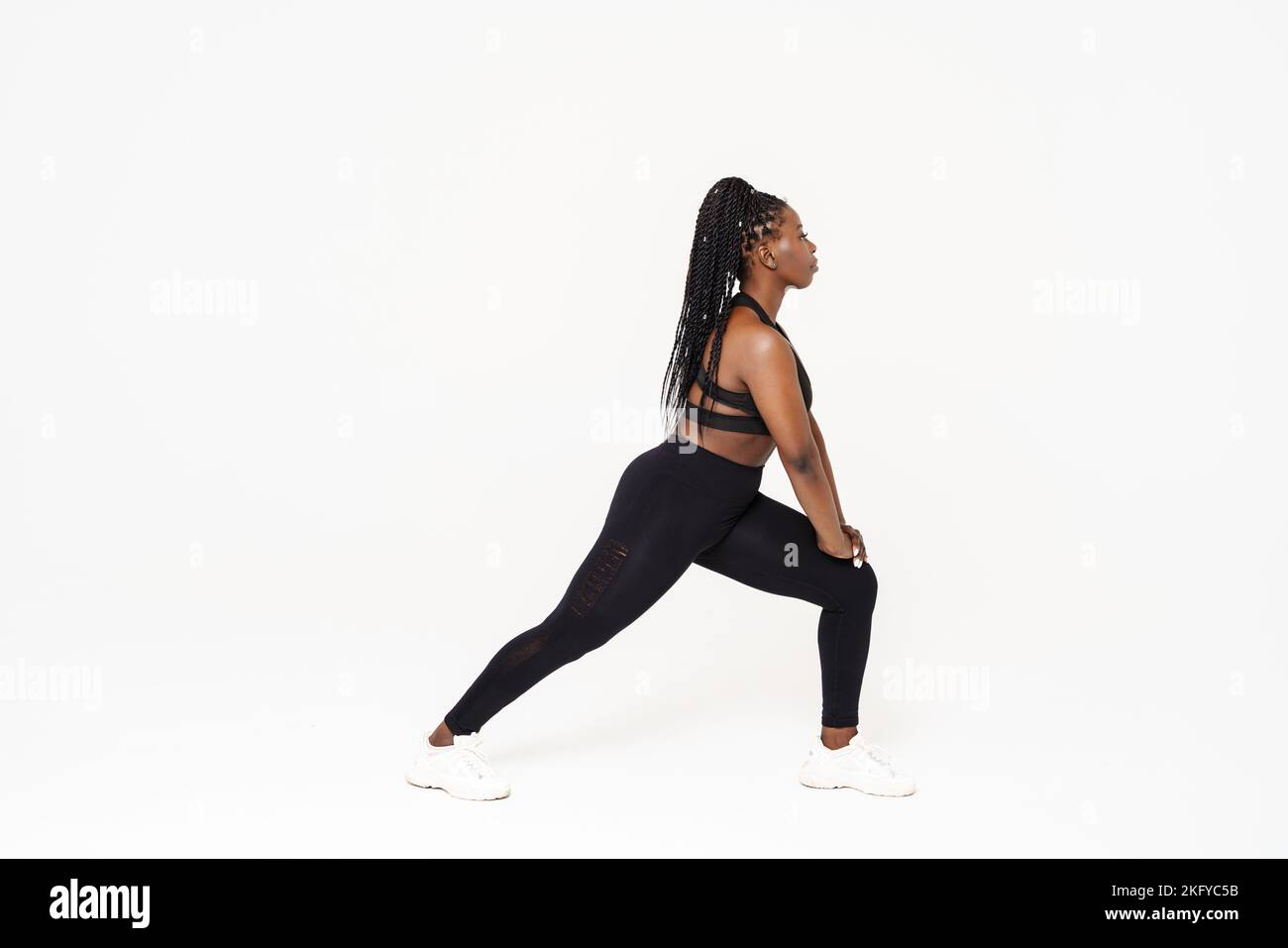 Black young woman doing exercise while working out isolated over white ...