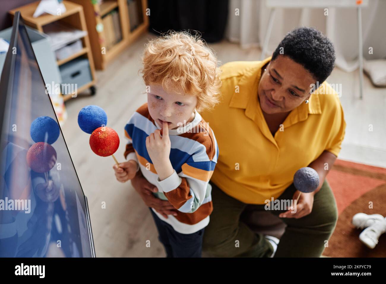 Cute pensive little boy with models of Earth and Mars looking at ...