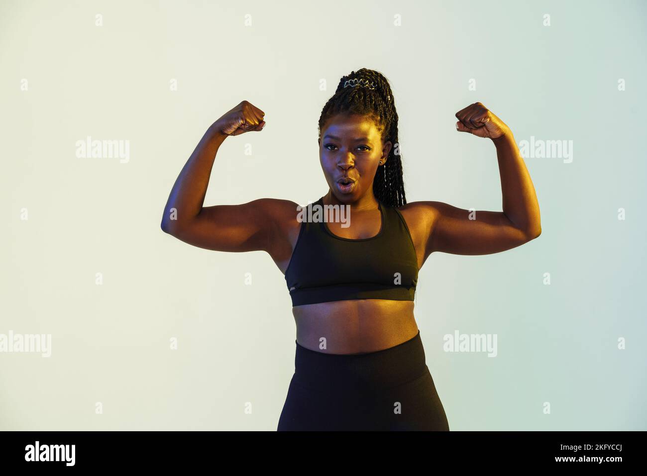 Black young sportswoman showing her biceps at camera isolated over ...