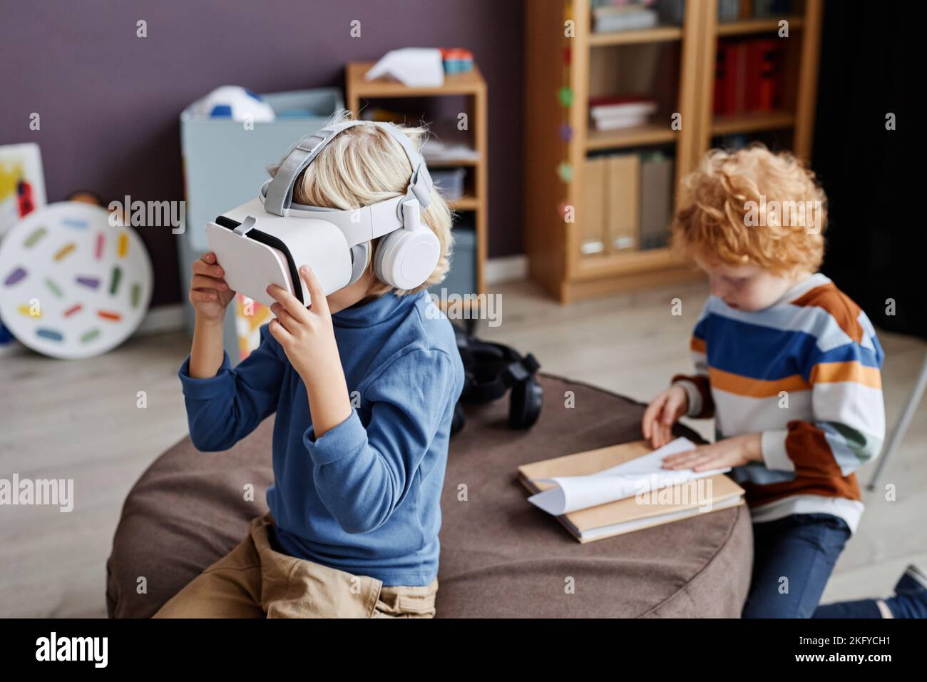 Adorable little learner of nursery school in vr headset playing virtual ...