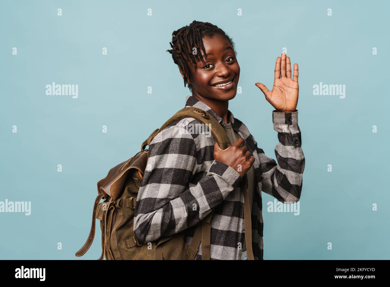 African american young woman wearing plaid shirt and backpack waving ...