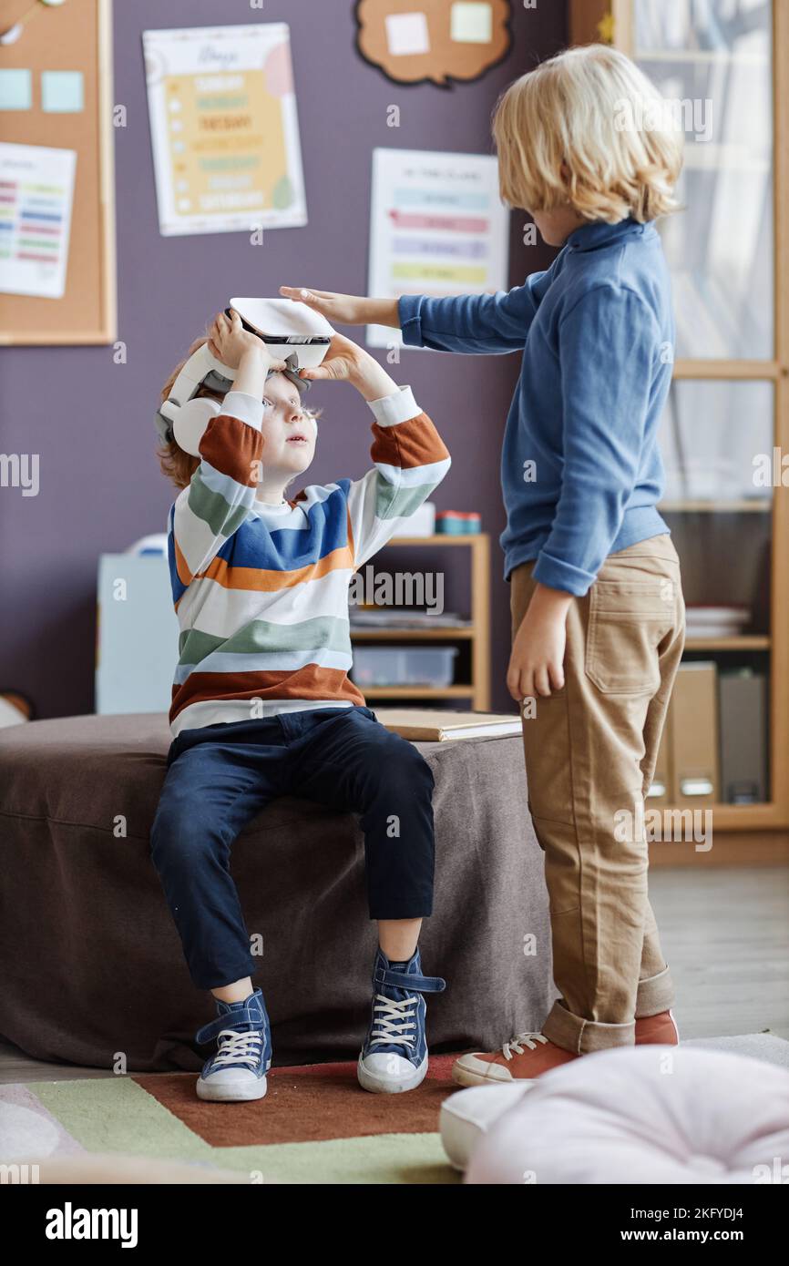 Two adorable learners of nursery school discussing virtual game while ...