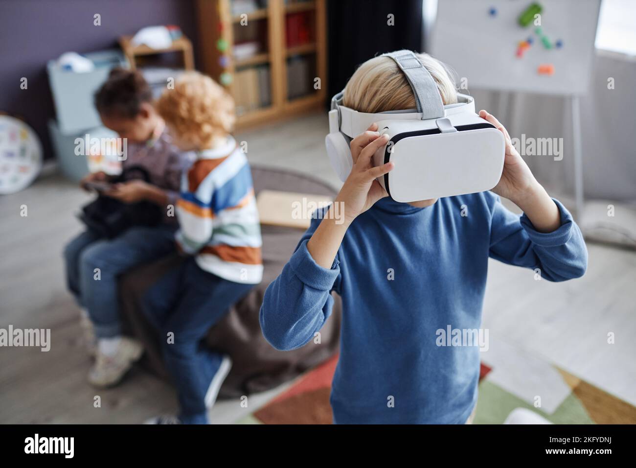Blond little boy in vr headset standing in front of camera and enjoying ...