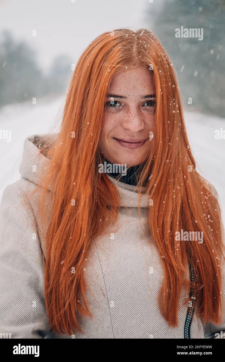 Portrait of a red-haired girl with freckles on her face. With blurred ...