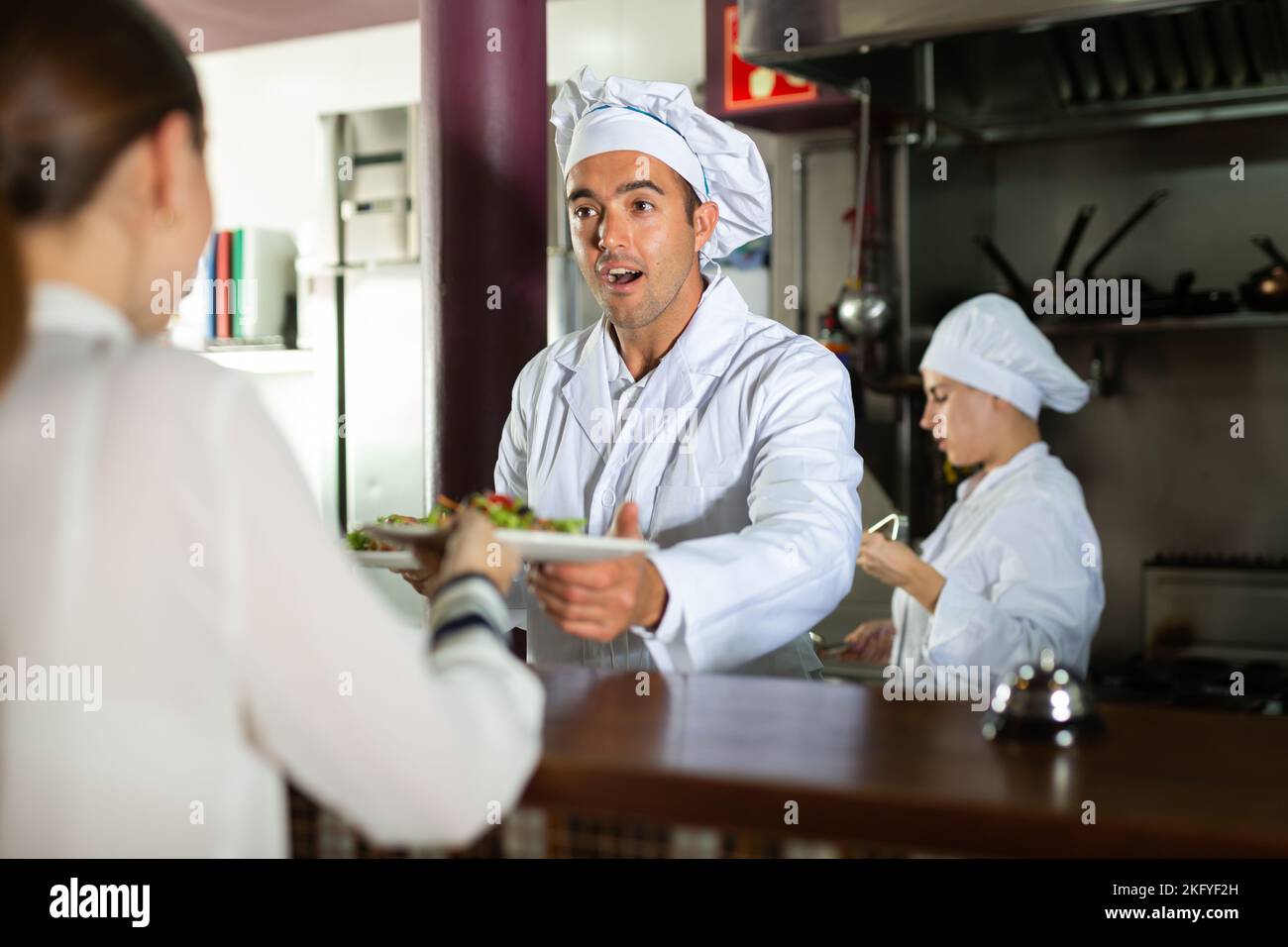 Chef giving out ready meals to waitress Stock Photo - Alamy