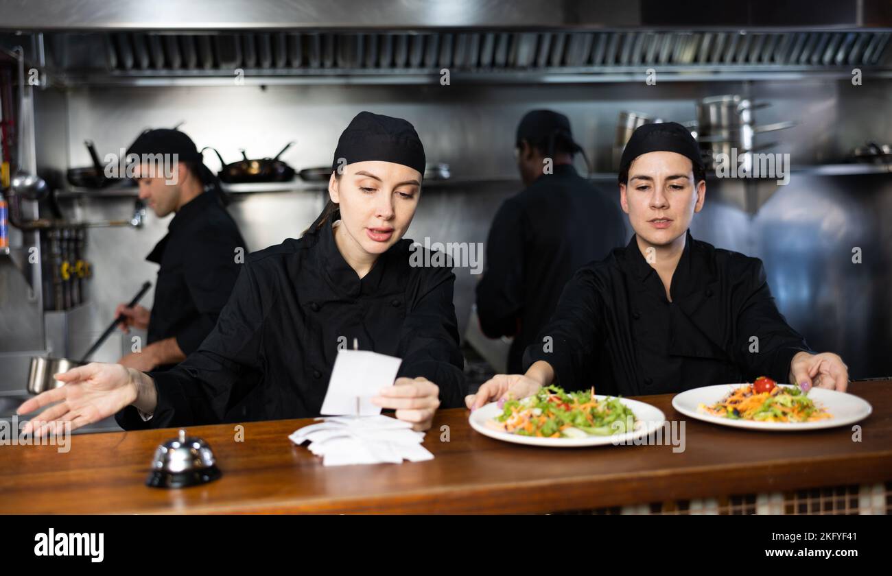 Chefs checking orders and giving out meals Stock Photo - Alamy