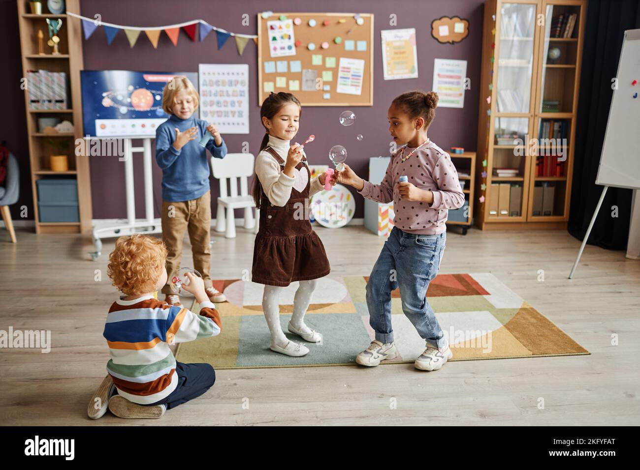 Group of little carefree kids in casualwear having fun with soap ...