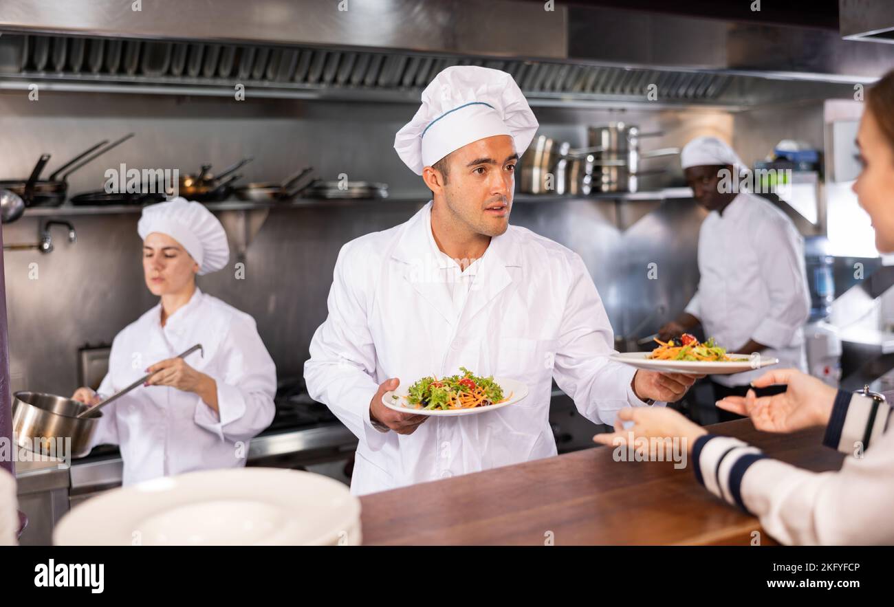Service process in cafe - chef serves ready meals to visitors of modern ...