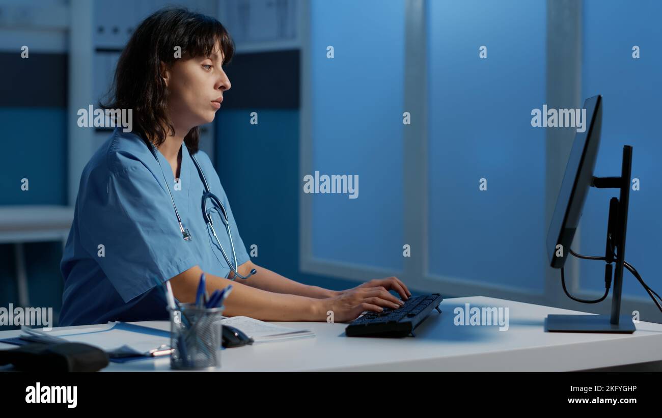 Stressed exhausted medical assistant standing at desk working after ...