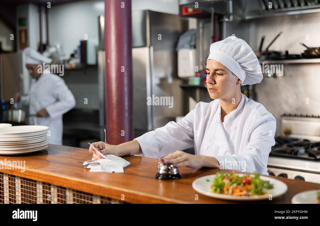Female chef reads the paid check and presses the bell for visitors to ...