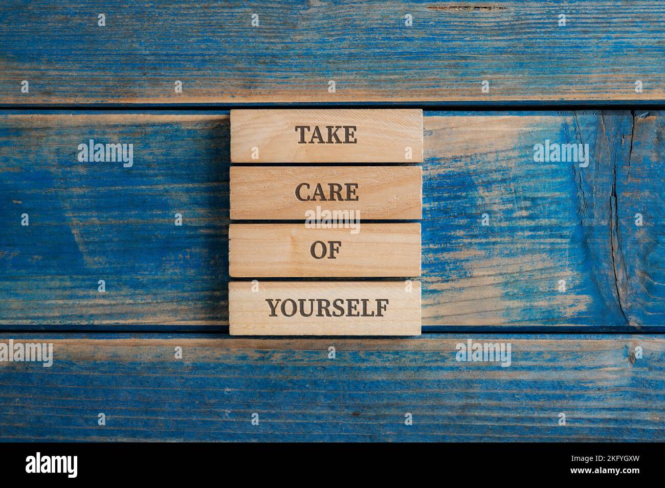 Take Care of Yourself sign written on four stacked wooden pegs placed ...