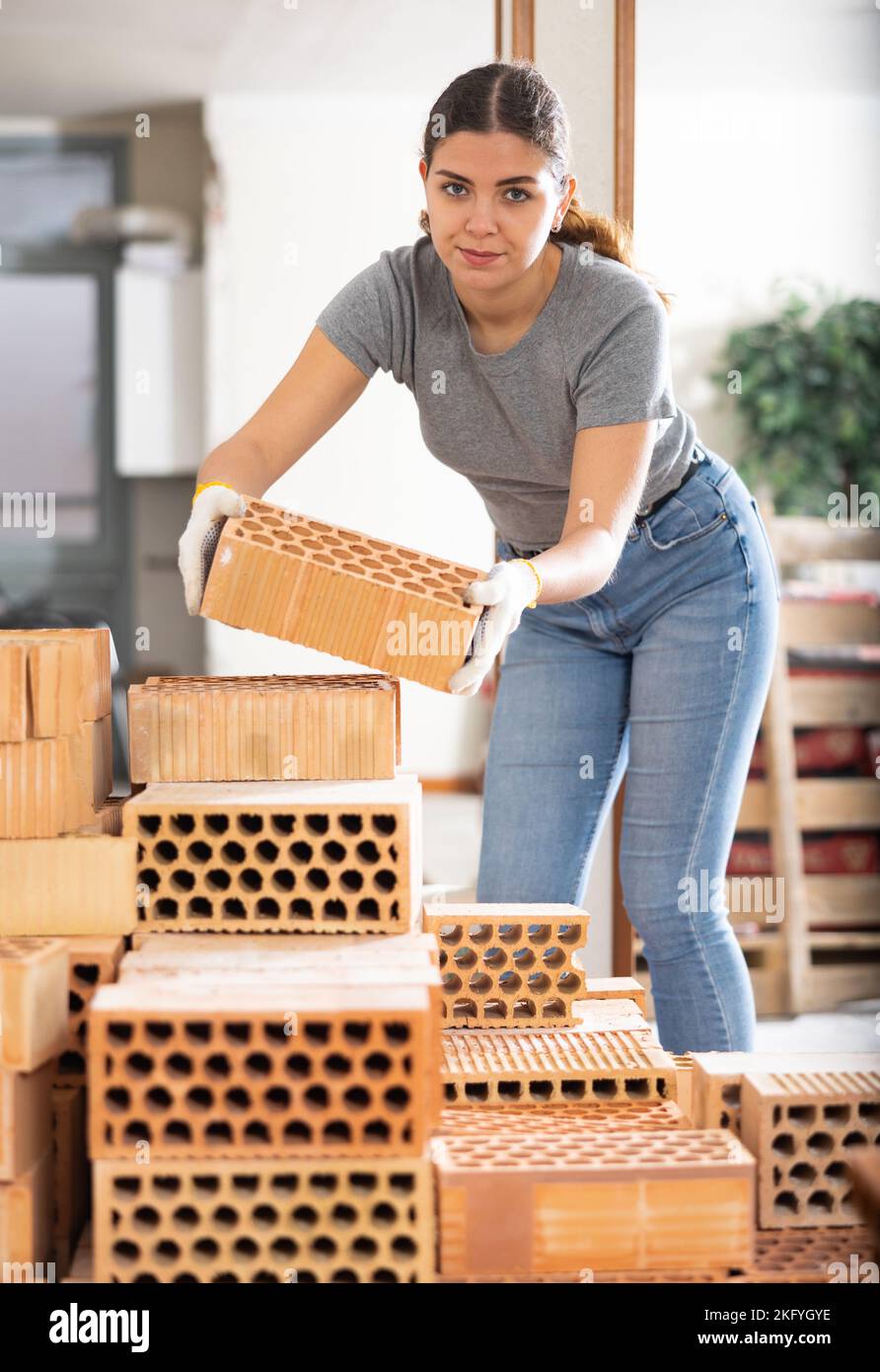 Young woman preparing bricks for masonry in house during renovation ...