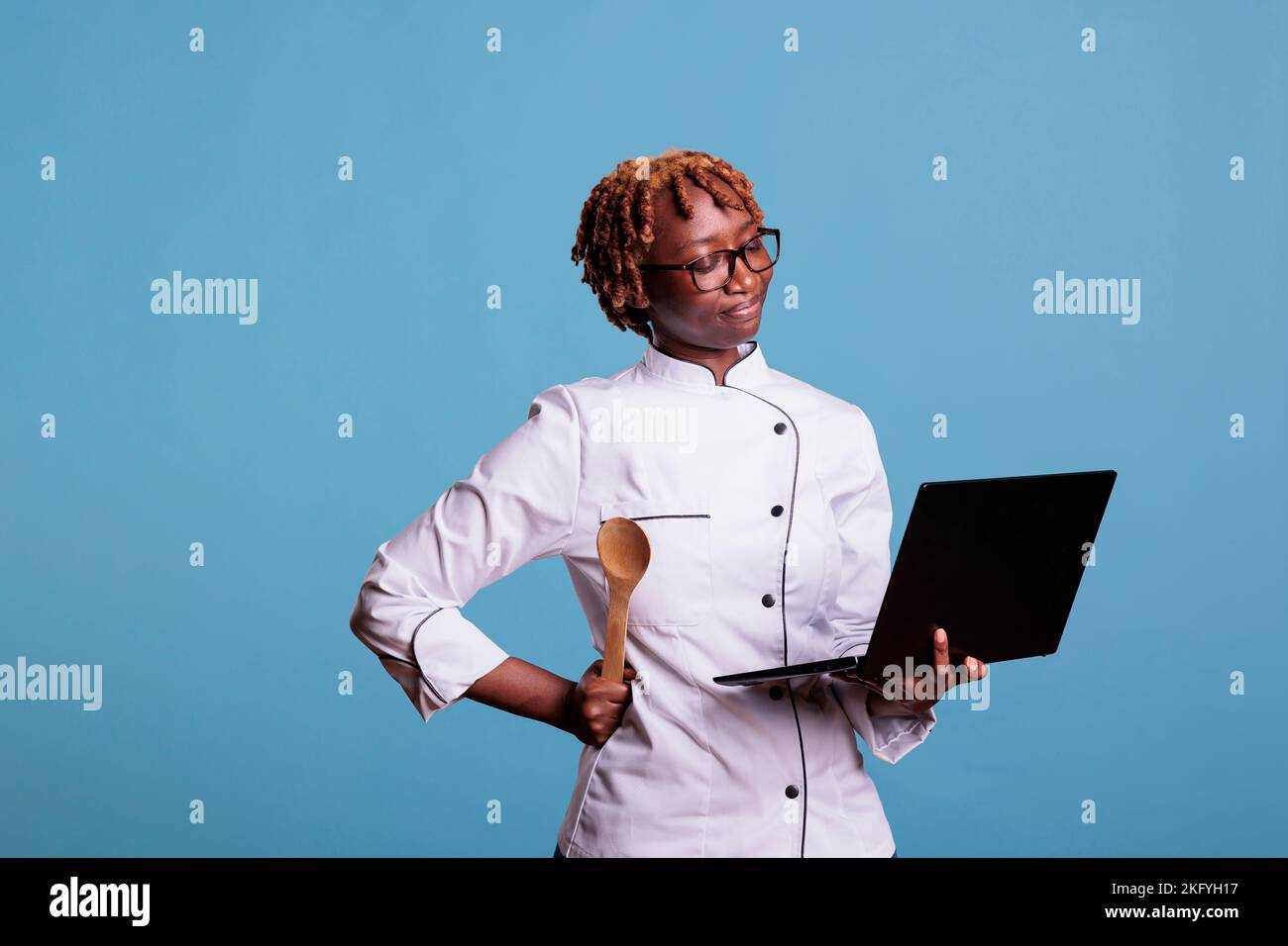 Food industry worker in kitchen uniform using computer to inspire a ...