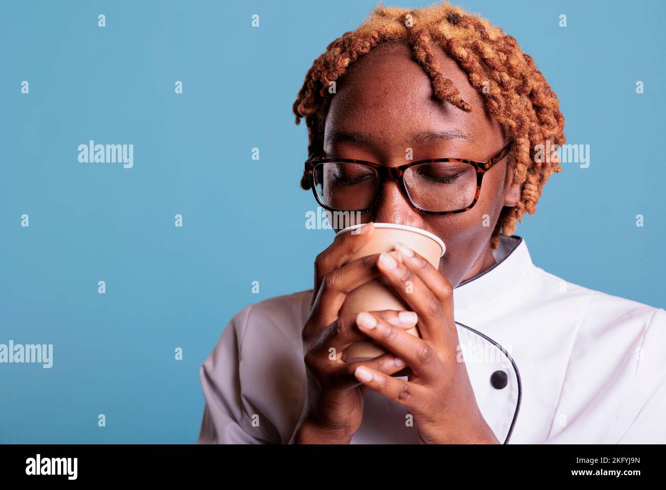 Successful female chef drinking coffee wearing kitchen uniform while ...