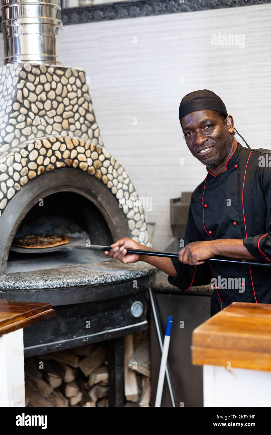 Portrait of african american chef man baking pizza in oven Stock Photo ...