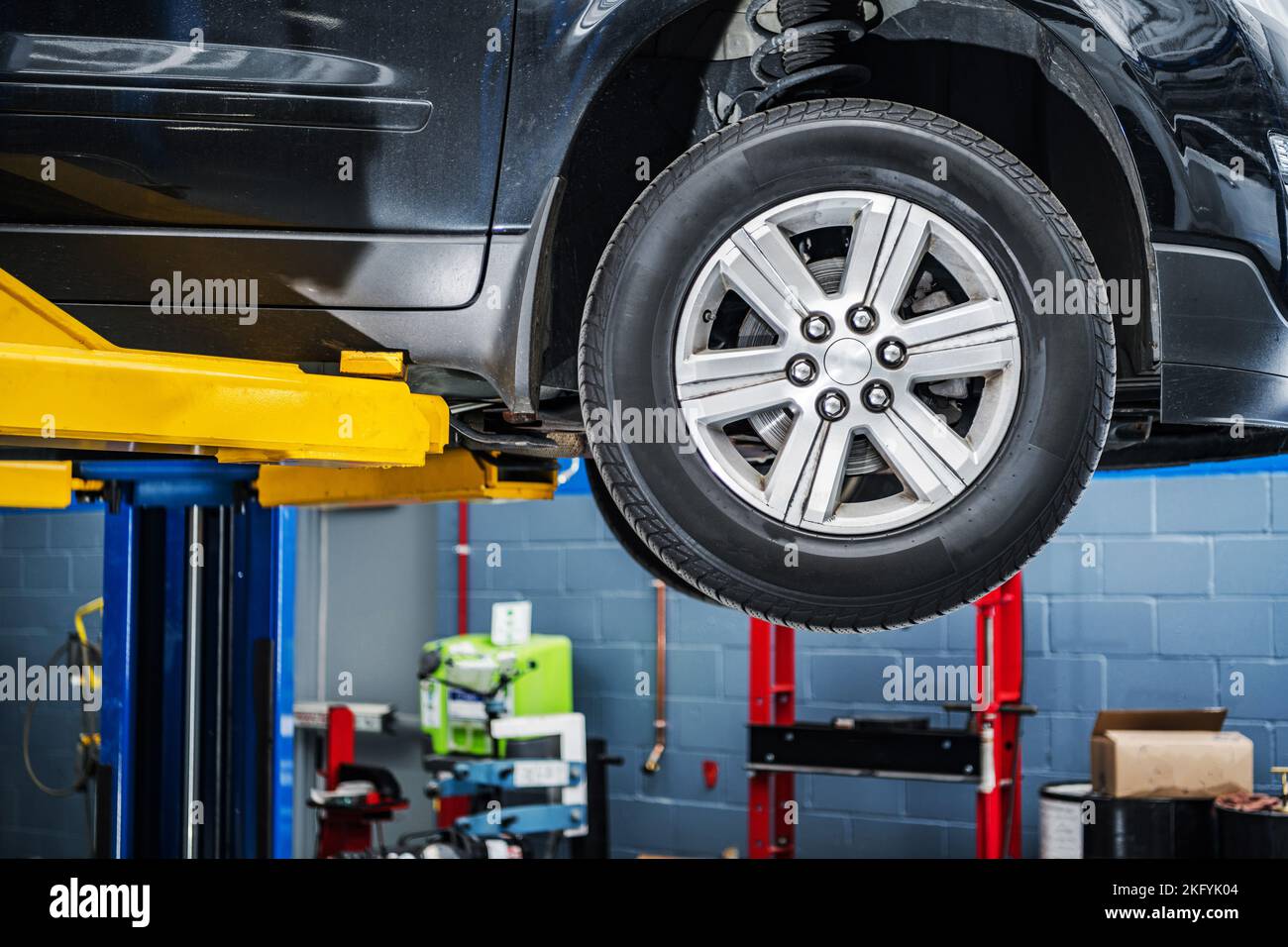 Vehicle Lifted on Car Lift in Automobile Workshop. Wheel Closeup ...