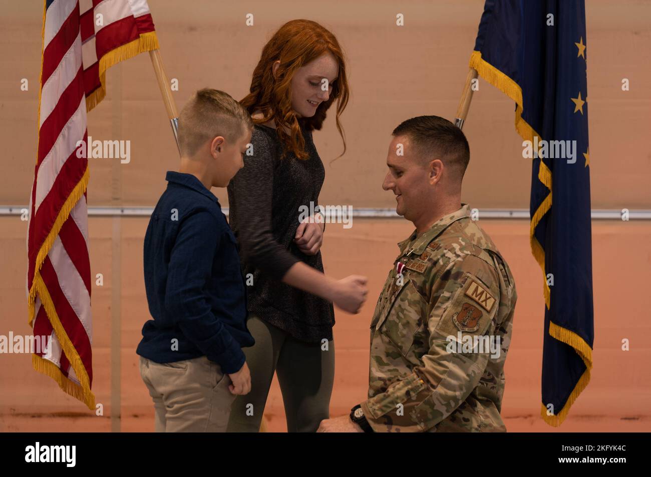 U.S. Air Force Maj. Cole Hoopingarner kneels as his children attach a ...