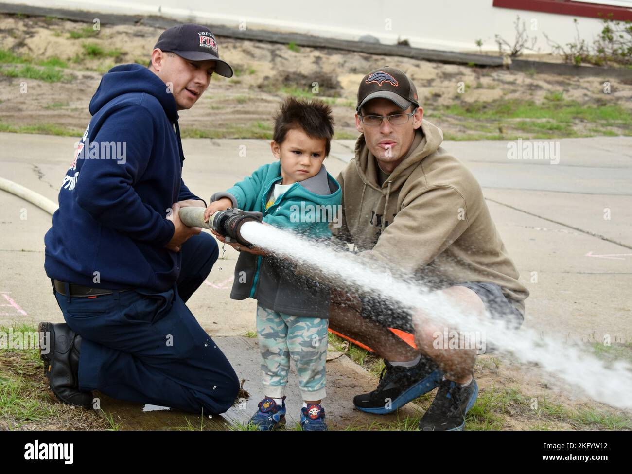Xavier Barrott, 2, operates a fire hose with some help from Firefighter ...