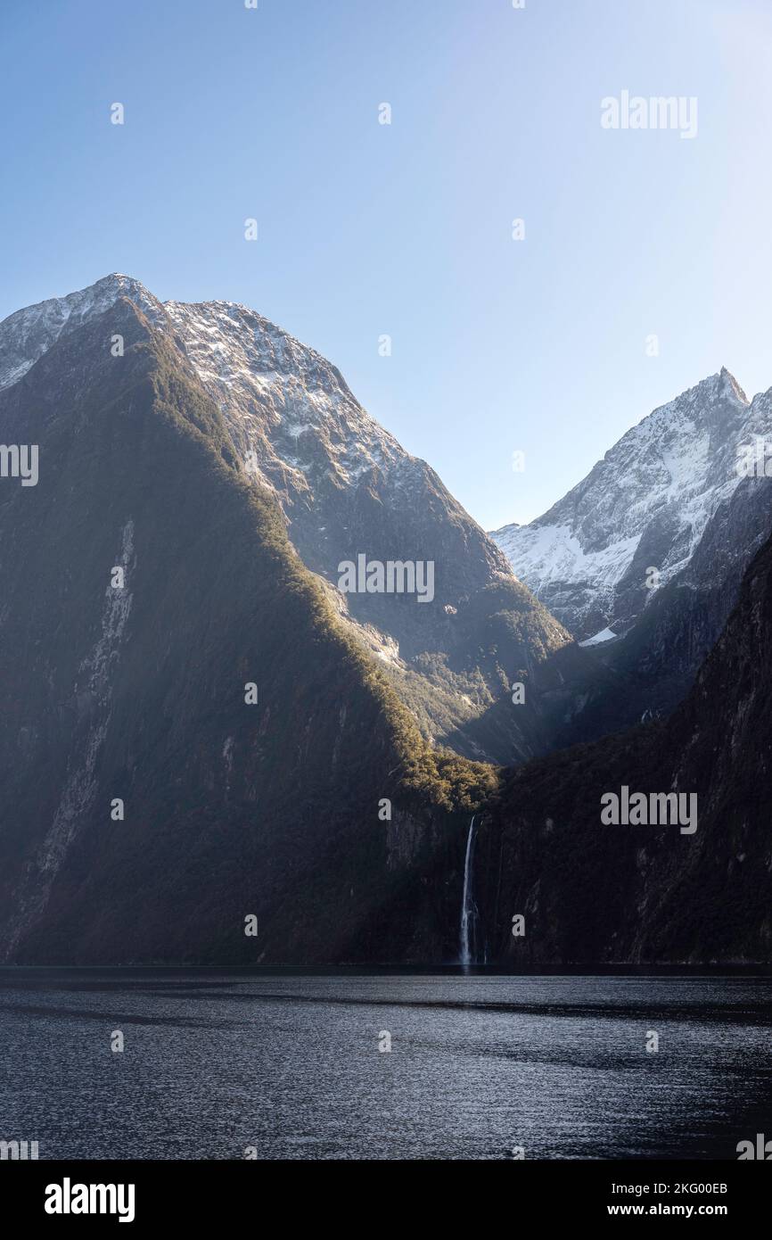The mountainous cliff walls of the Milford Sound tower over the nearly ...