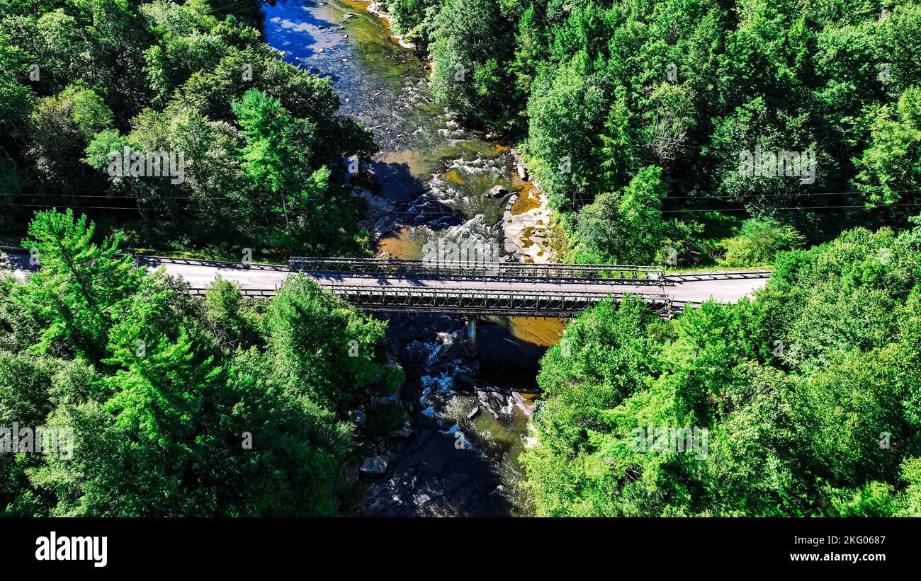 An aerial view of a bright over a rocky river flowing through dense ...