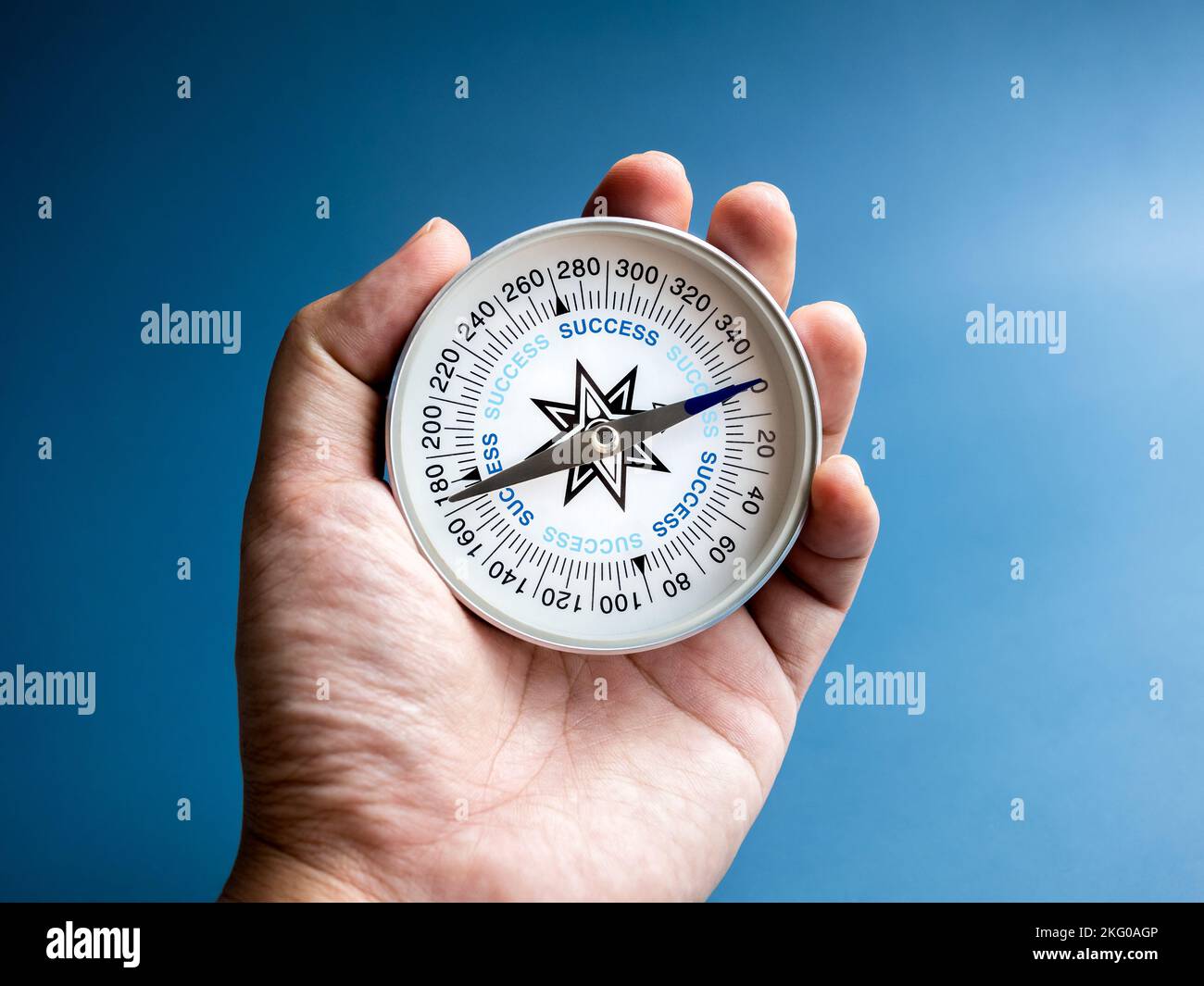 Closeup blue words "SUCCESS" on compass in businessman's hand on blue ...
