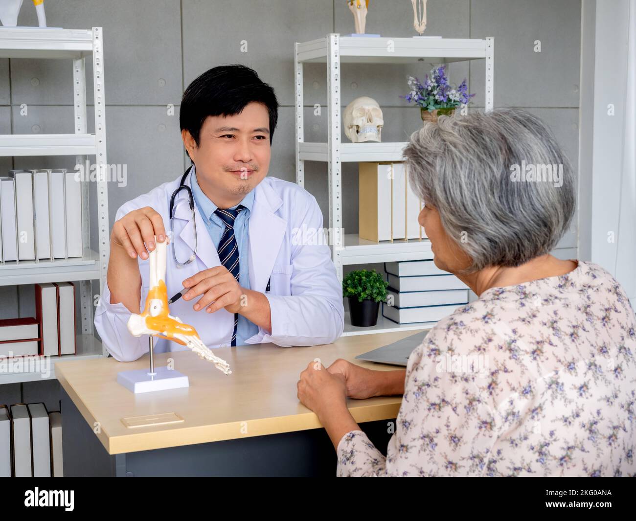 Smiling professional Asian man orthopedic doctor pointing to foot ...