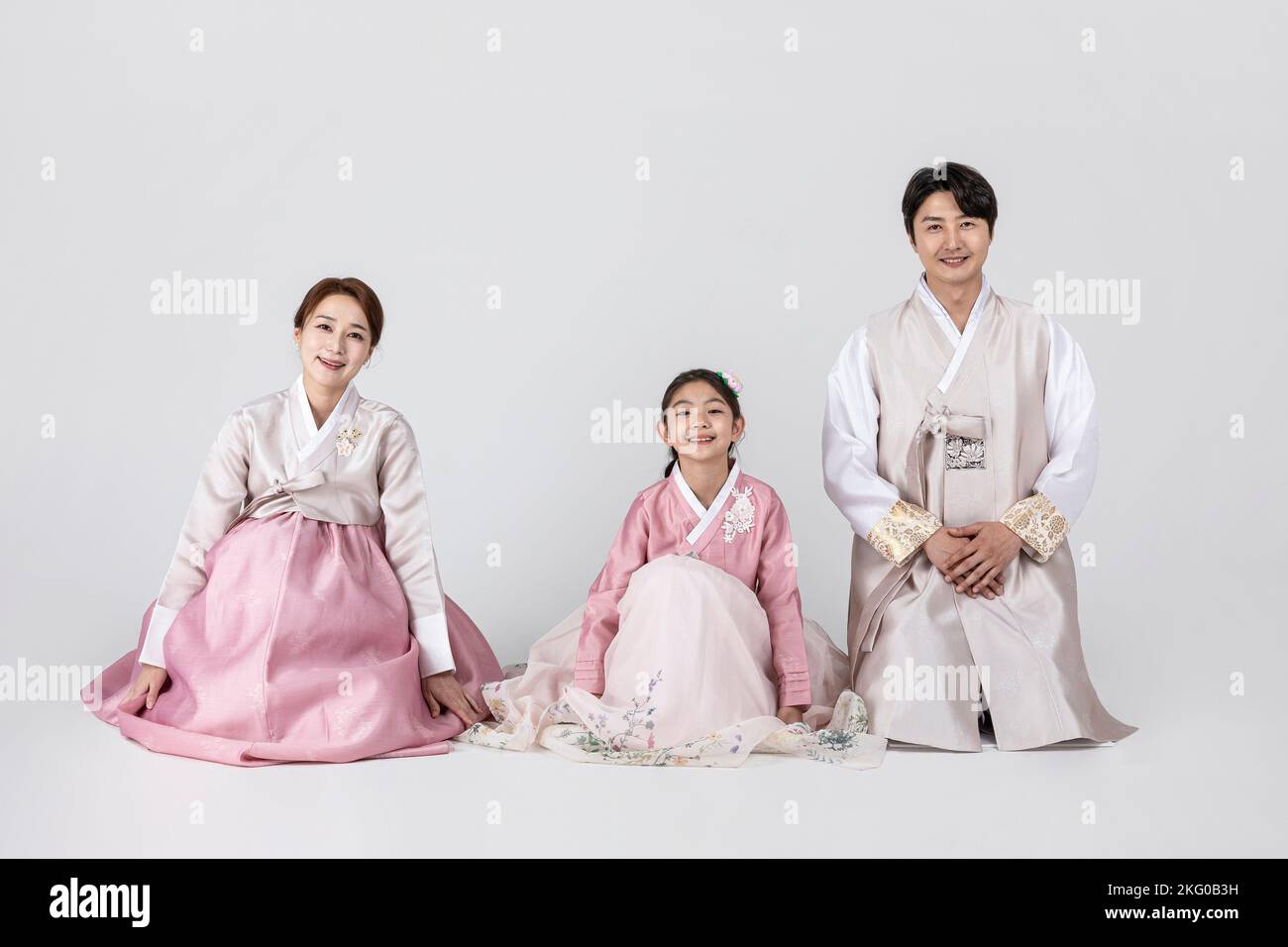 Korean family in Hanbok, isolated white background sitting side by side ...