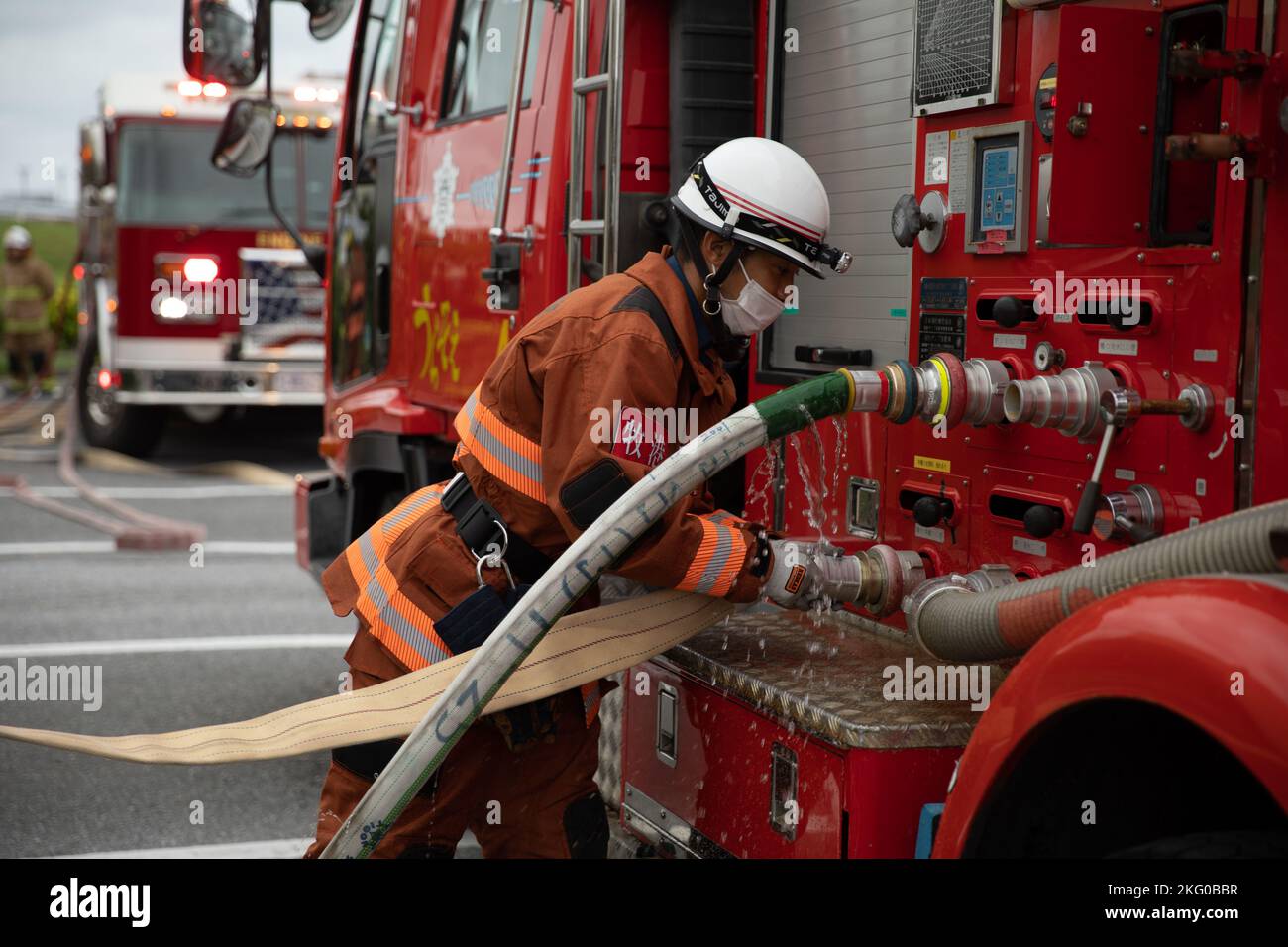 A firefighter with the Urasoe Fire Department connects a fire hose to a ...