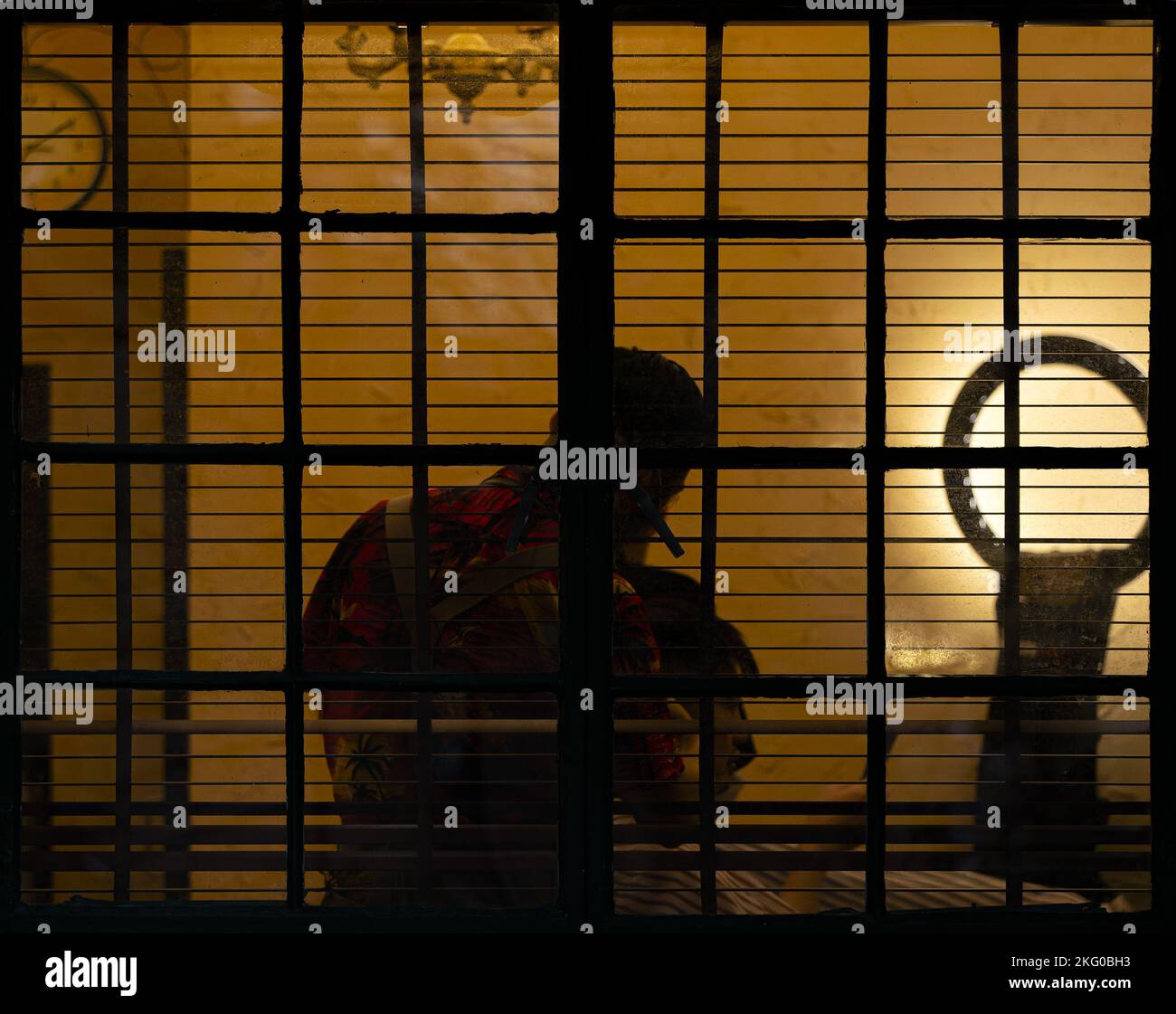 A man cut a customer's hair in the dim yellow light Stock Photo - Alamy