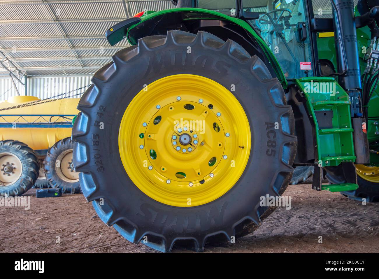 A large rear tractor wheel and tyre from side on, in a large open shed ...
