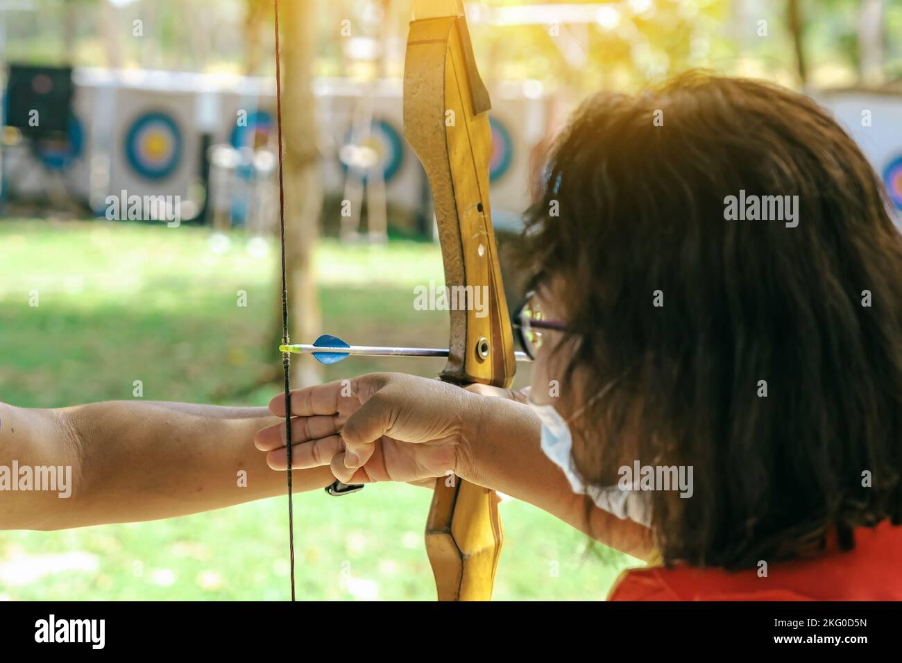 Female teacher teaches student to aim at goal. An archer teaching young ...