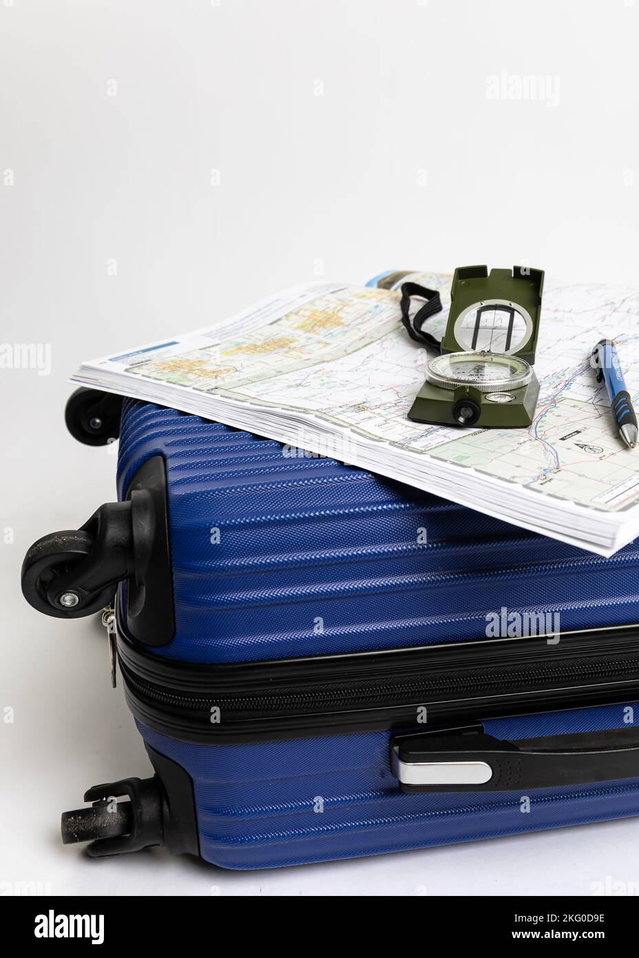 A blue travel suitcase is displayed next to maps, compass and pen, all ...
