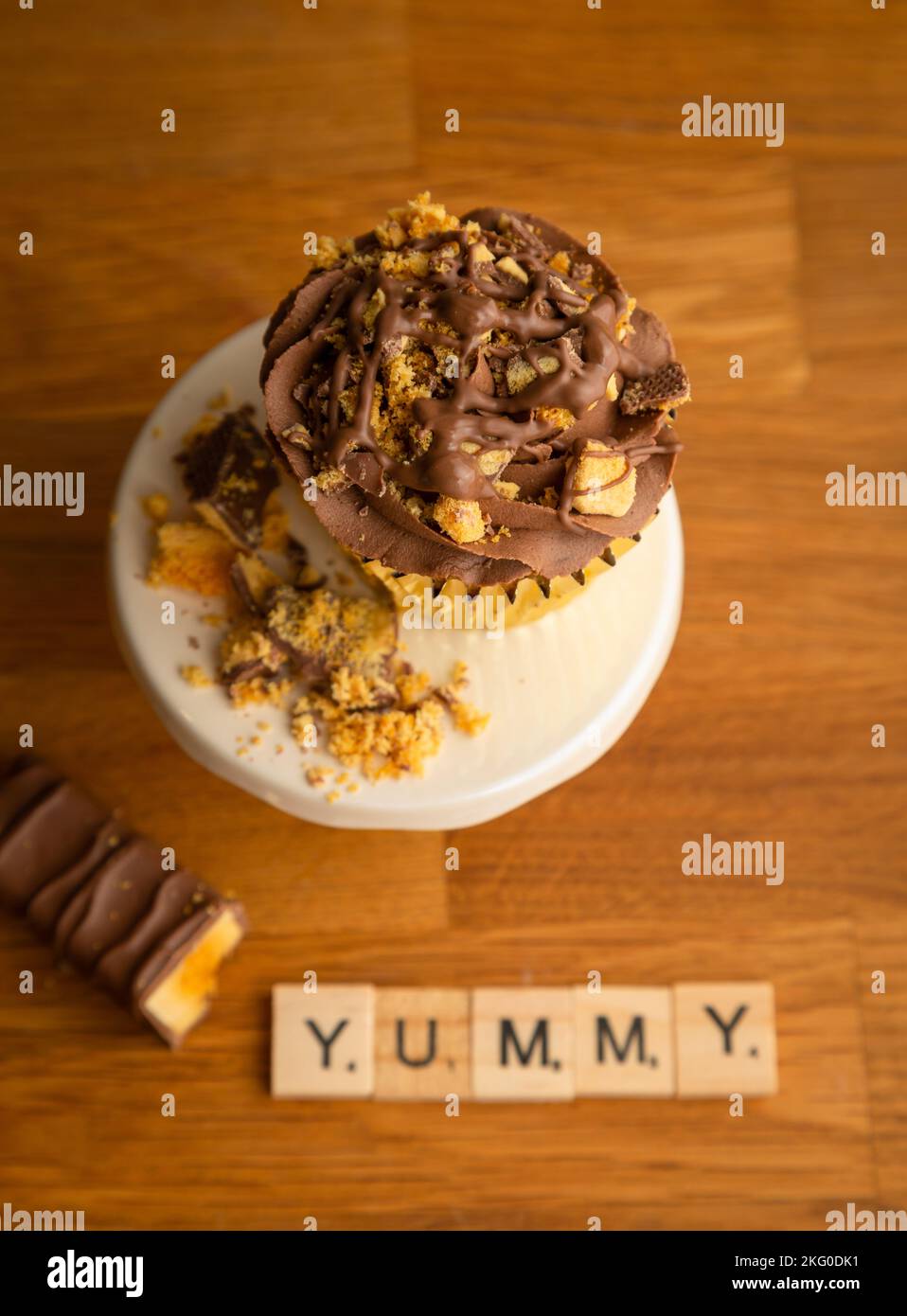 A vertical closeup of a cupcake with chocolate frosting, and wooden ...