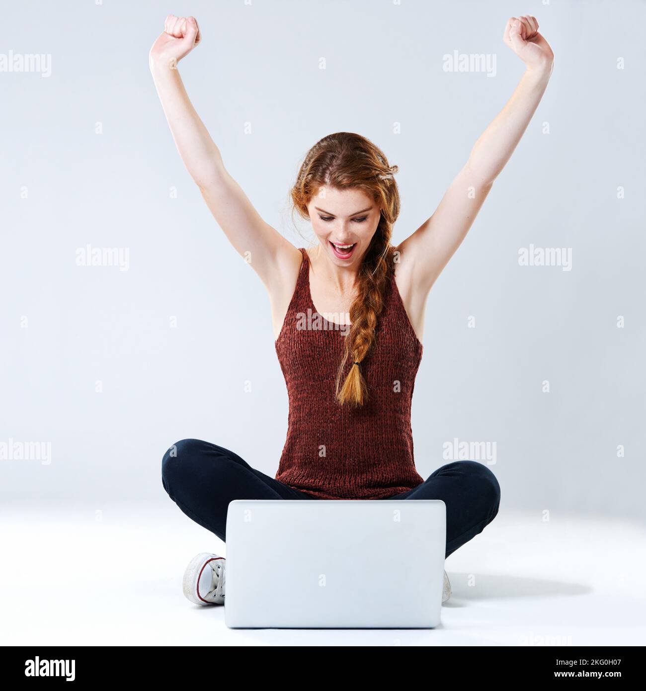 Thats so exciting. Studio shot of an excited young woman sitting with ...