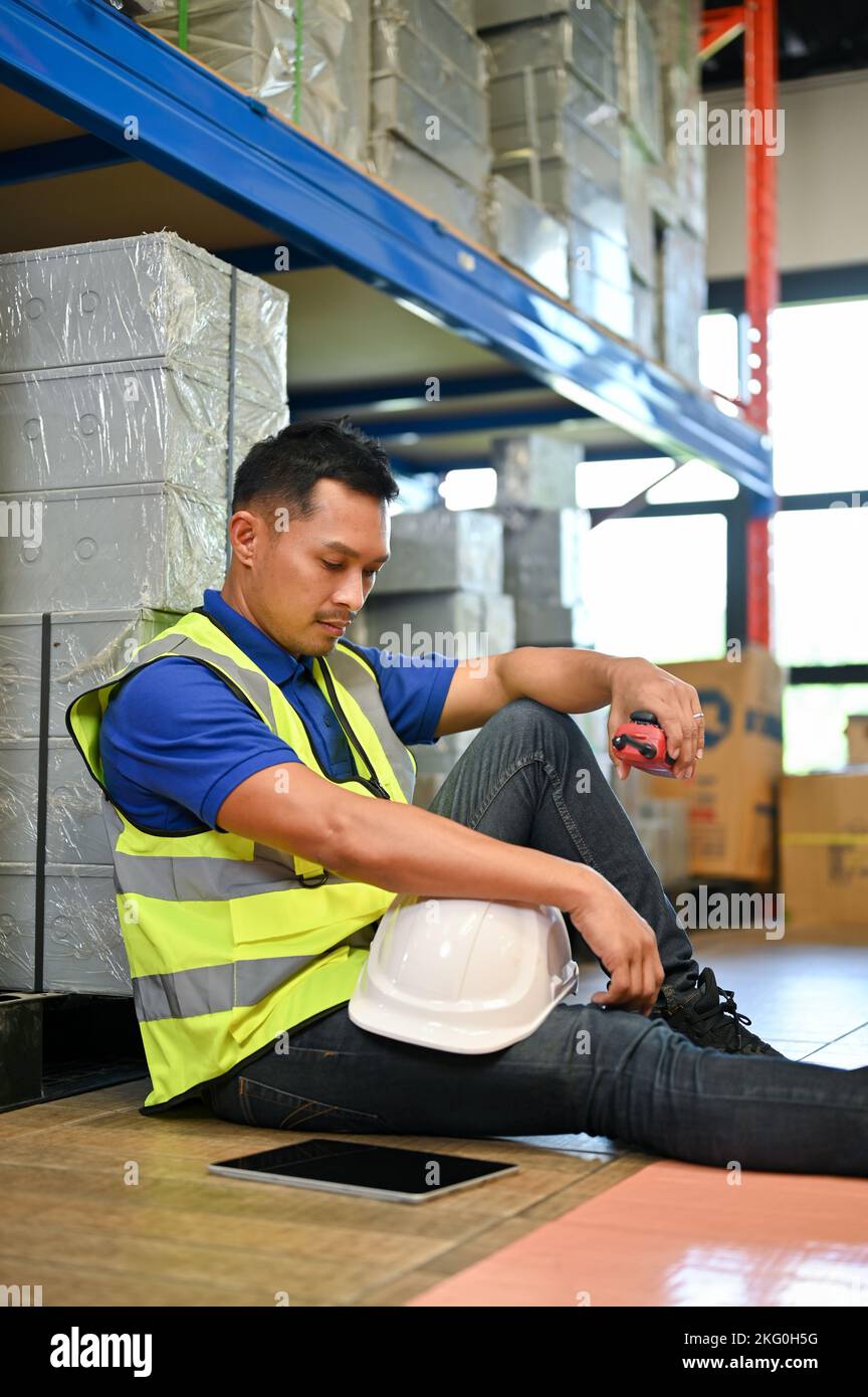 Portrait, Tired and upset millennial Asian male warehouse worker ...