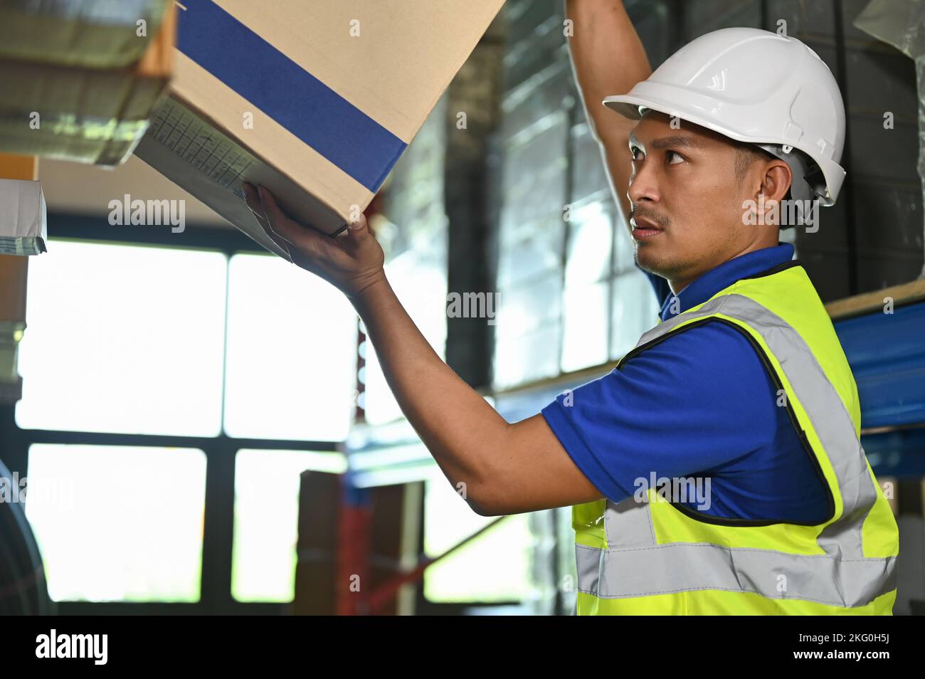 Concentrated millennial Asian male warehouse worker in uniform and ...