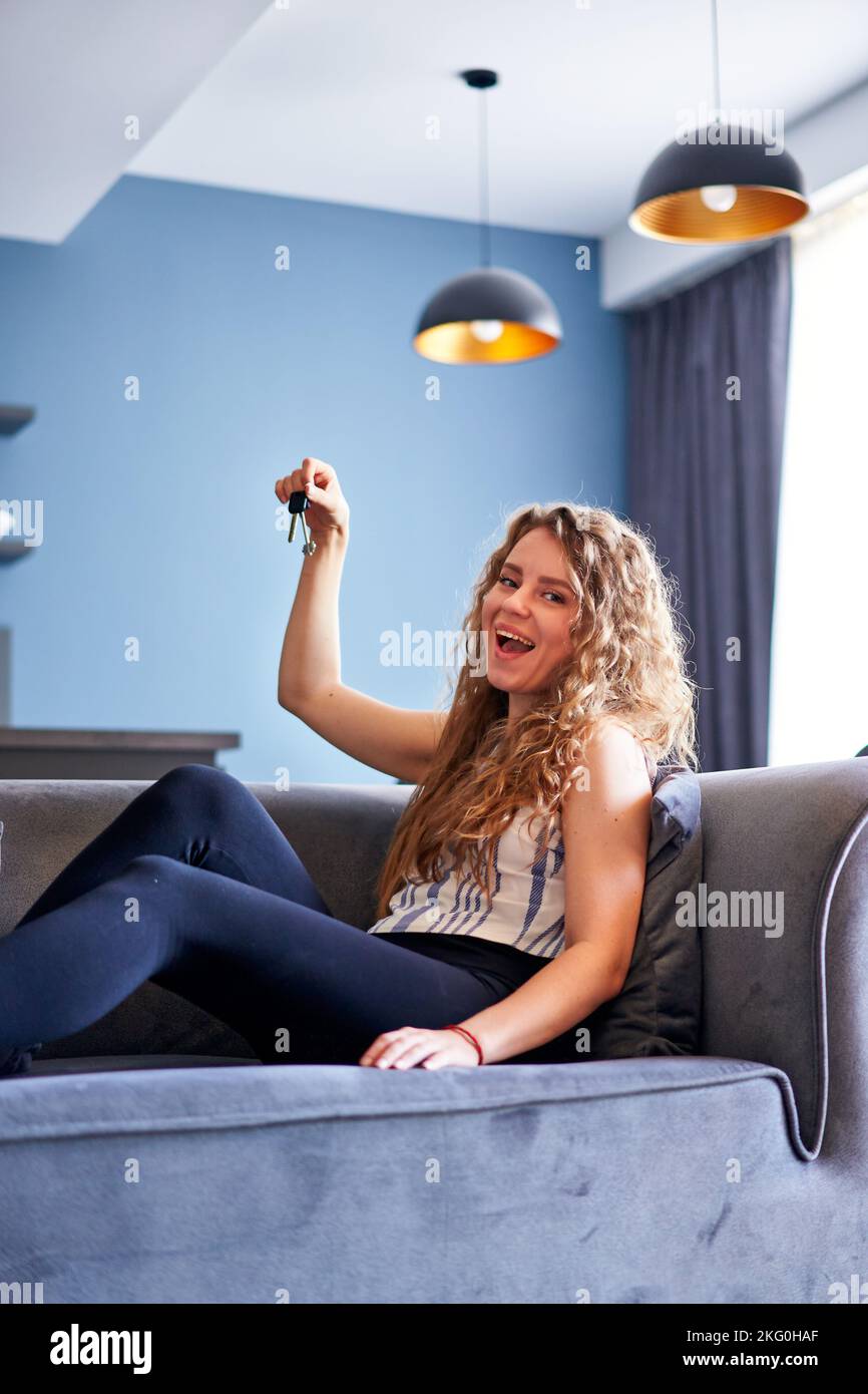 Happy woman showing new house or apartment keys sitting on sofa. Female ...