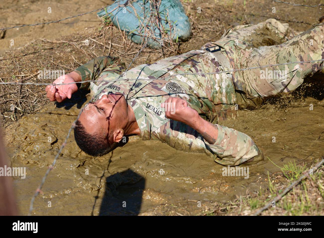 First Sgt. Christopher Stevens low crawls on his back under barbed wire ...