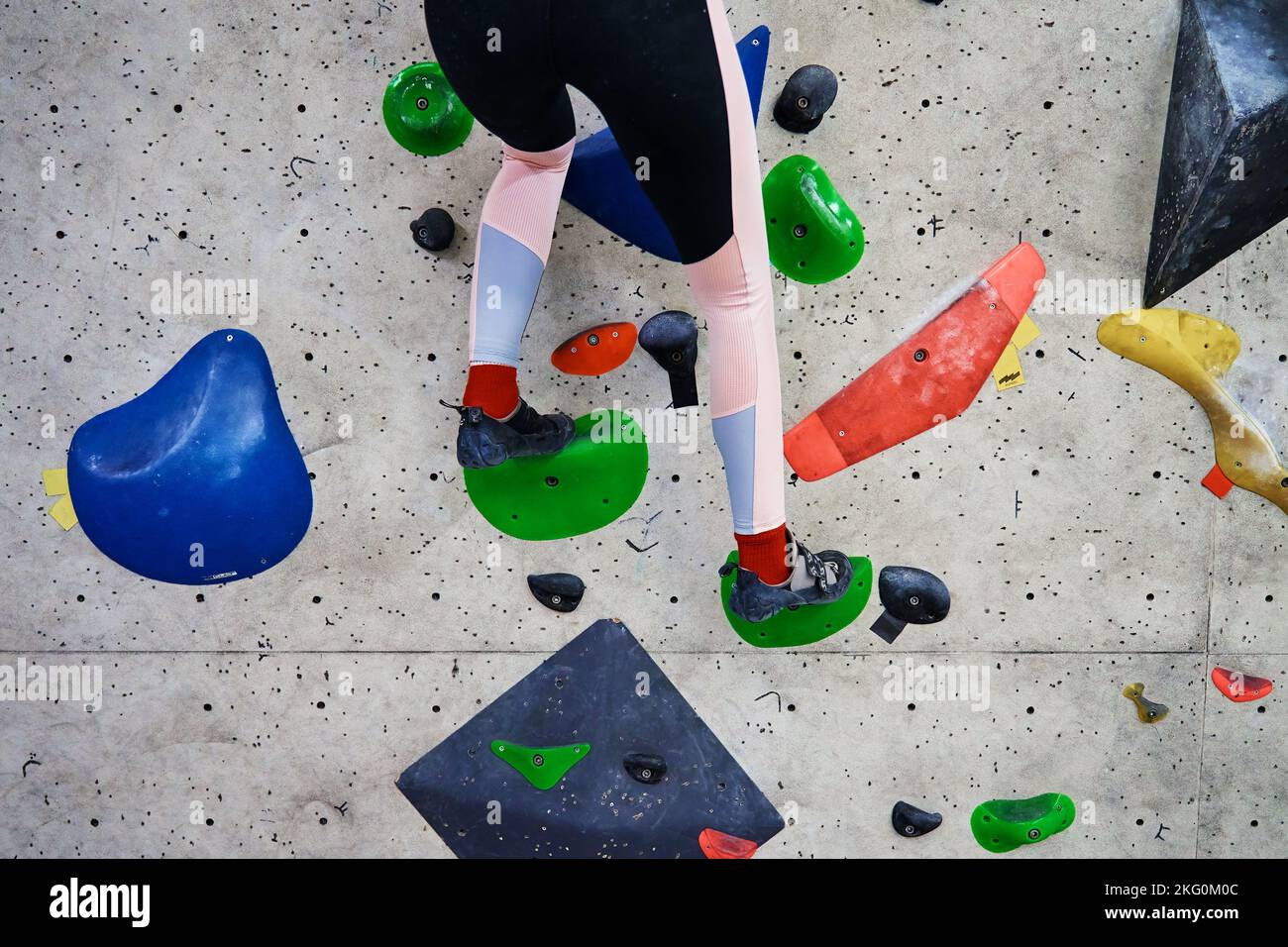 Woman climbing up on wall at bouldering gym. Female climber training ...