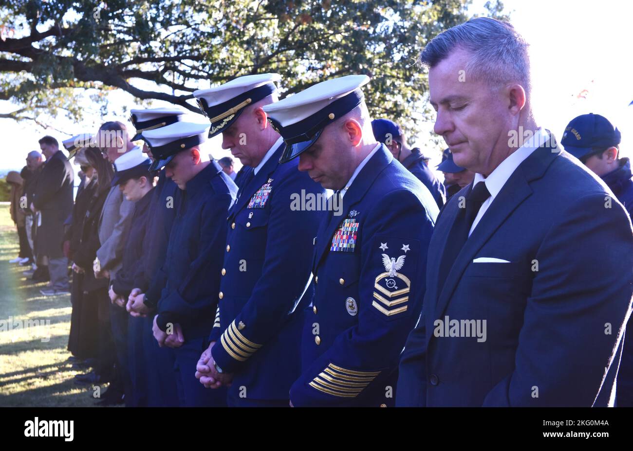 Coast Guard members, family, and friends bow their heads in remembrance ...