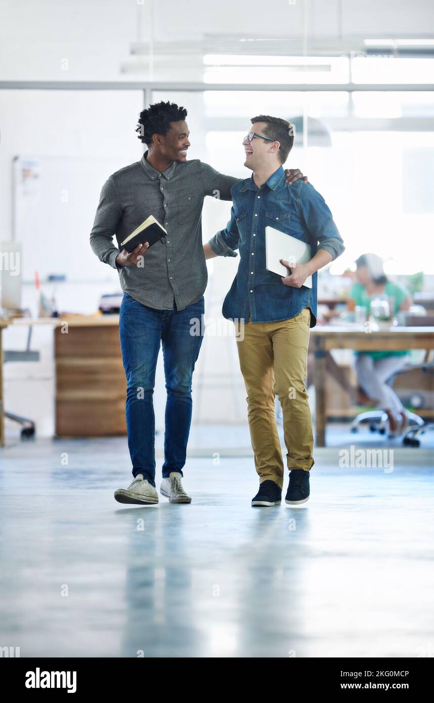 Great job. a two young businessmen talking while walking through their ...