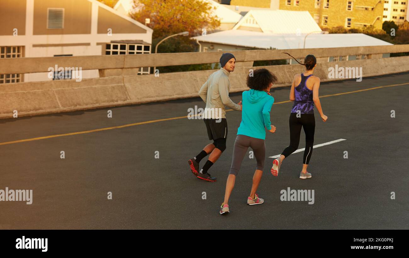Supporting each others run. Rearview shot of a group of joggers running ...