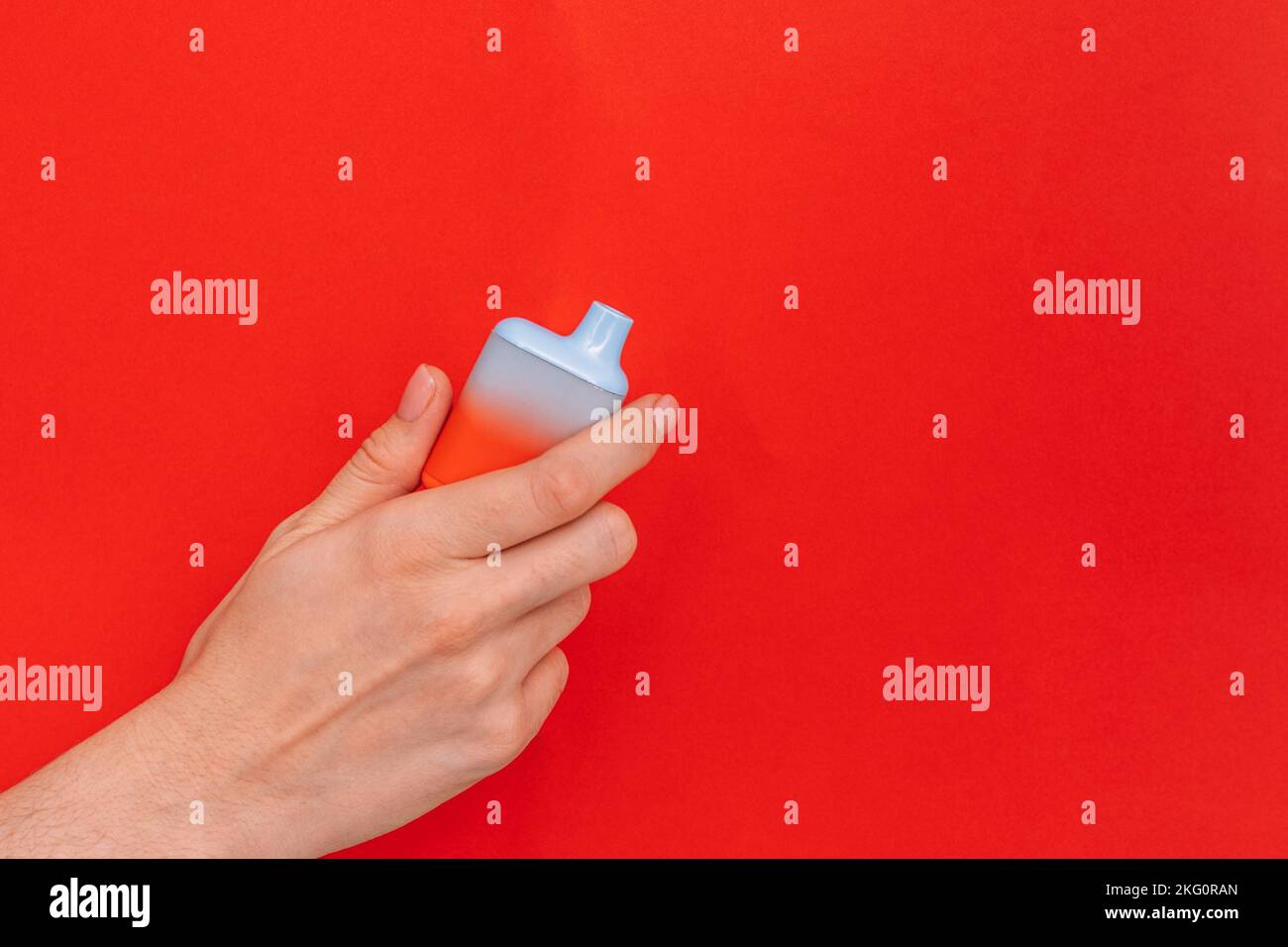Vape in female hand against red background Stock Photo - Alamy